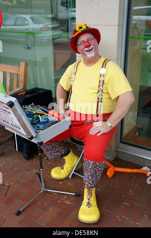 middle-aged man with a clown nose and spiky gray hair leans over a ...