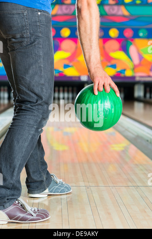 Young man in bowling alley having fun, the sporty man holding a bowling ...