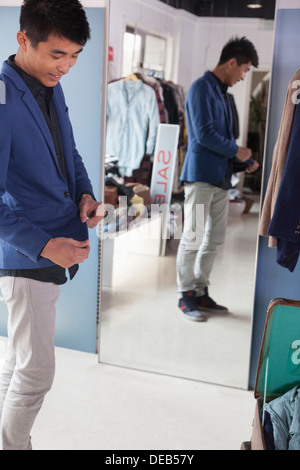 man trying jacket on at mirror in clothing store Stock Photo - Alamy
