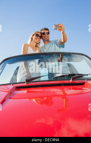 Picture of smiling couple man and woman 30s looking at laptop on table ...