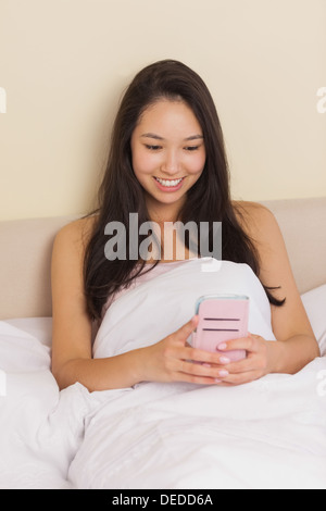 Asian woman using smartphone at home sitting on comfortable sofa ...