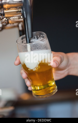 Hand holding glass filling beer Stock Photo - Alamy