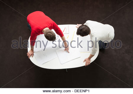 Two people leaning over a table laid outside with a white cloth and a ...