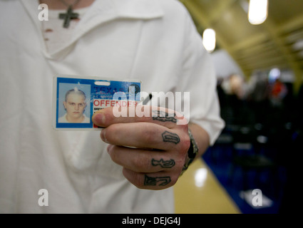 A white male prison inmate with various tattoo on his hand, holds up ...