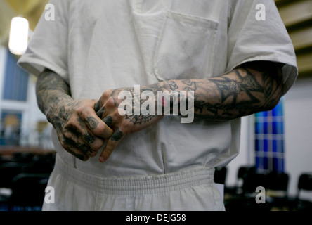 A white male prison inmate with various tattoo on his hand, holds up ...