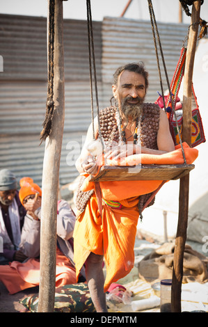 Sadhu standing on one leg on the support of swing at Maha Kumbh ...