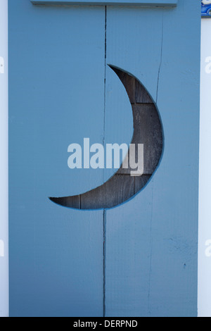 A cutout crescent moon decorates a window shutter on a Cape Cod home ...