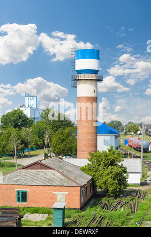 White brick water tower against the blue sky. Old building with small ...