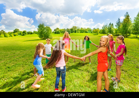 Large group of girls play roundelay and stand in circle in the park on ...