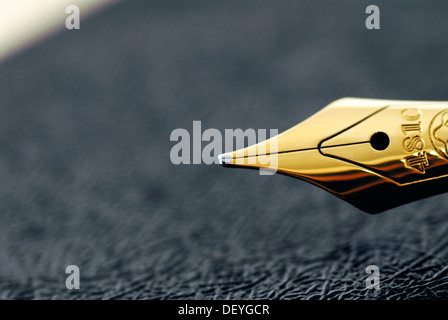 Fountain pen on a notebook. Black ink splash. Wooden table. Copy space ...