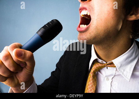 Young man with microphone on blue studio background, leading concept ...