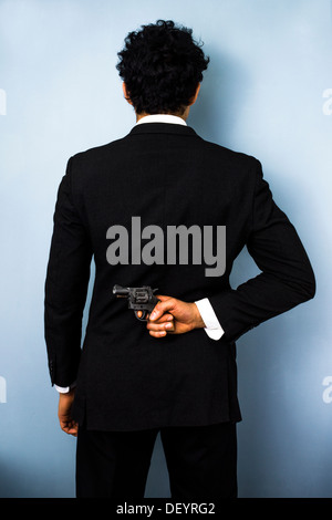 Man hiding gun behind his back Stock Photo - Alamy