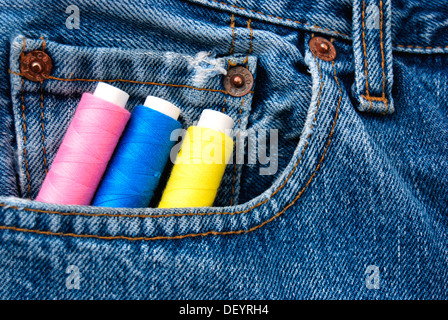 Reels with colorful sewing threads with jeans in the background, sewing ...