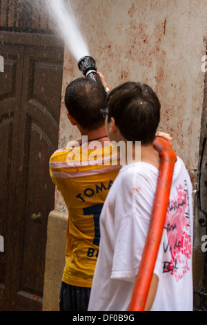 Men Spraying fire hose to clean up after Tomatina Stock Photo - Alamy
