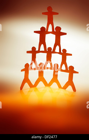 Human team pyramid on orange background Stock Photo - Alamy