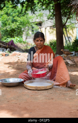Rural Indian village woman sifting Finger Millet flour / Ragi flour ...