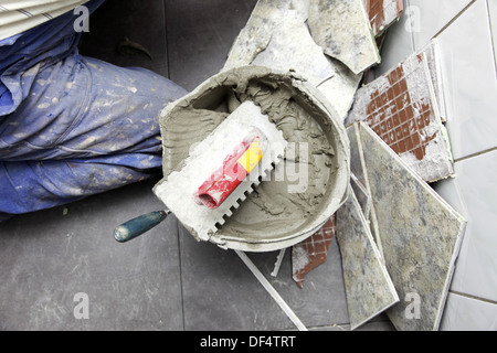 a tiler at work. bonding of floor tile with tile adhesive and filler ...