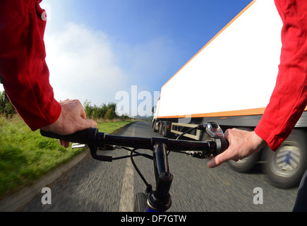 articulated lorry overtaking cyclist riding mountain bike on country ...