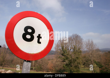A weight restriction warning sign at one end of a small rope bridge ...