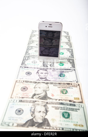 Cash for your iphone. U.S. currency and a used iphone on a white ...