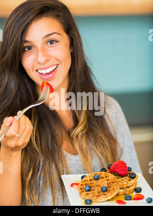 Thoughtful woman eating a fruit salad looking very happy Stock Photo ...