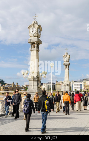 People walk along La Concha beach on a clear winter day in San ...