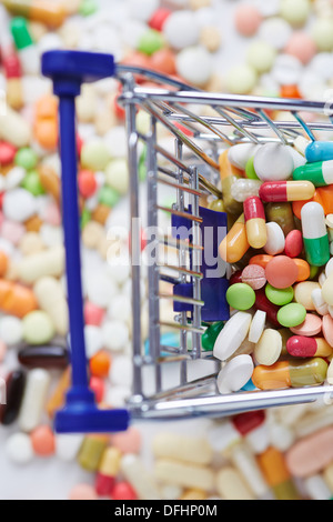Shopping cart with different medical pills and capsules in it on pink ...