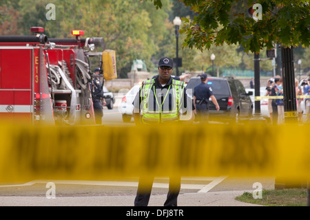 Policeman standing behind police line tape at a crime scene ...