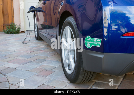 Plug-in electric car with carpool sticker plugged into an EV charging ...