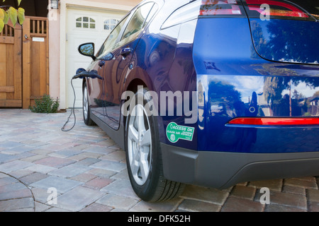 Plug-in electric car with carpool sticker plugged into an EV charging ...