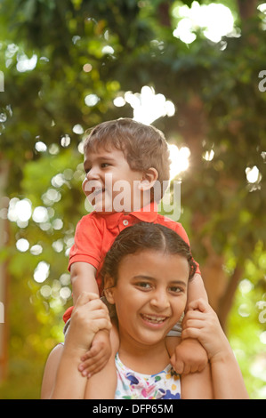 Boy carrying brother on shoulders at field Stock Photo - Alamy