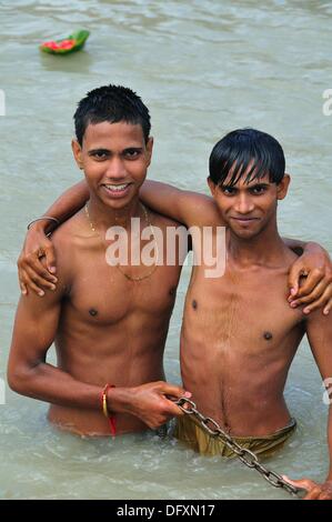 Indian young man bathing and praying in the sacred Ganges River next to ...