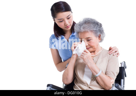 Female nursing worker comforting weeping senior woman Stock Photo - Alamy