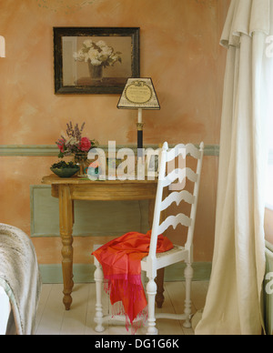 Living room with small pine table and box between neutral curtains ...