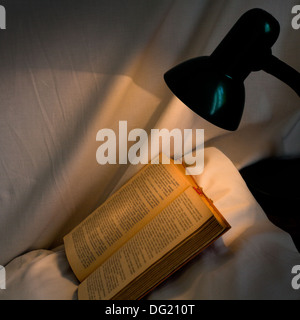 book on pillow lit reading lamp at night Stock Photo - Alamy