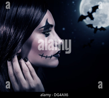 Girl with face-paint and Halloween witch costume over a white ...