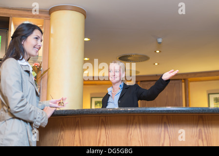 Beautiful friendly smiling receptionist behind the service desk in a ...