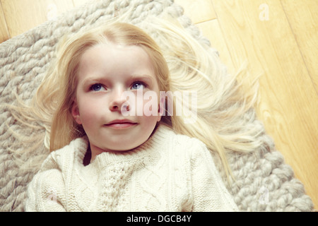 Young girl lying on rug Stock Photo - Alamy