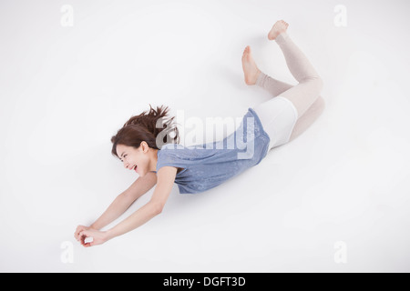An Asian woman is lying on the ground in a field in a brown sweater ...