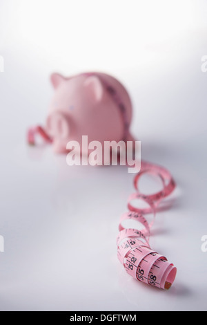 a pink piggy bank with a measurement band Stock Photo - Alamy