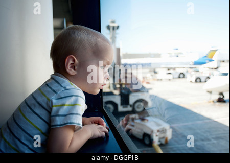 Toddler boy leaning on window reflection. Baby infant standing to ...