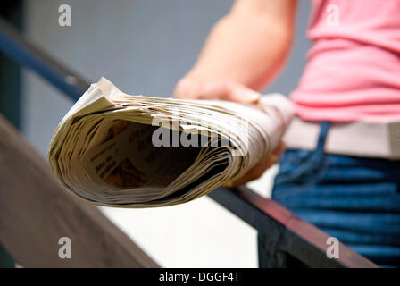 Hand holding rolled up newspaper, side view Stock Photo - Alamy