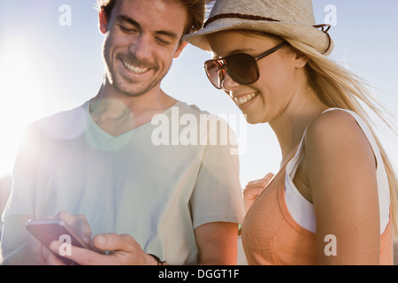 Young couple looking at a smartphone on a sunny day in the city Stock ...