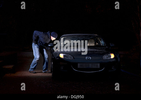 A man breaking into a parked car at night Stock Photo - Alamy