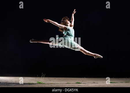 Female ballet dancer leaping mid air with legs in front, studio shot ...