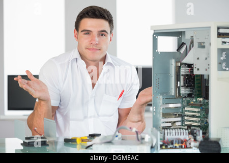 Confused, puzzled computer technician, a handsome young man, looking at ...
