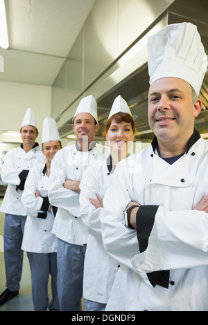 Smiling chef looking at camera with team working behind Stock Photo - Alamy