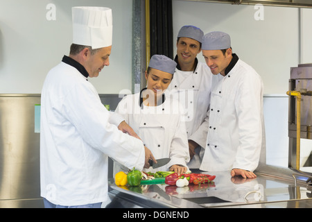 head-chef teaching colleagues how to slice vegetables in kitchen Stock ...