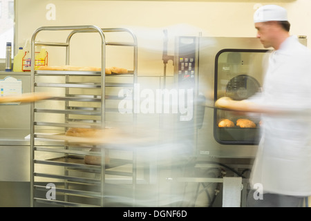 Two male bakers working in a bakery interior, one holding a tray with ...