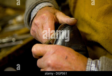 A shoemaker cuts the sole of a Shoe with a shoemaker's automatic cutter ...